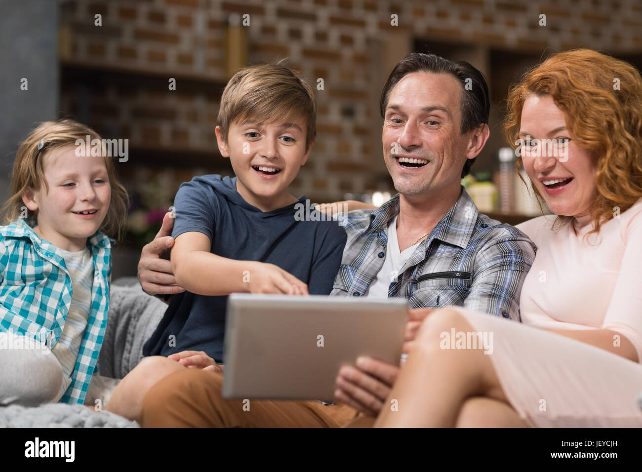 Happy Smiling Family Use Tablet Computer Sitting On Couch In Living ...