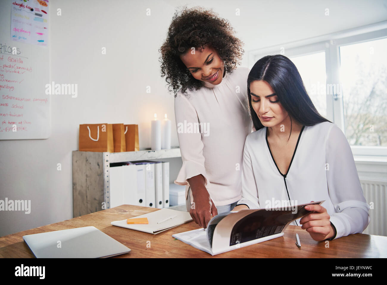 Two young women running a small business working on paperwork together ...