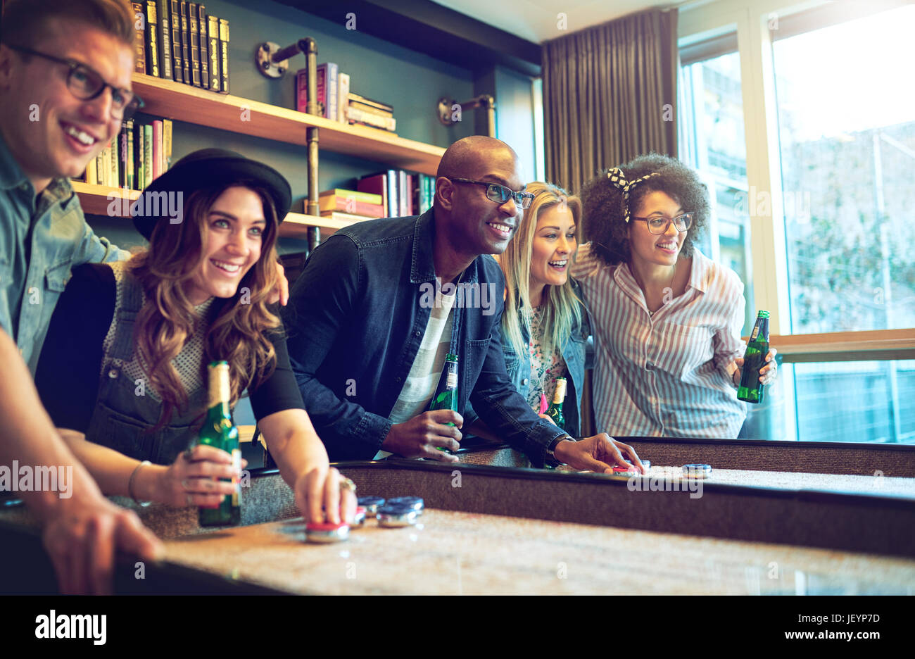 Group of mixed race friends having fun at bar playing a game and ...