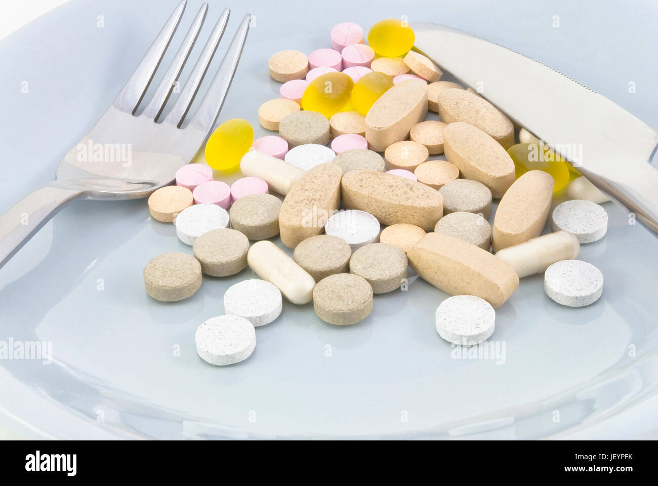 A mixture of pills on a light blue plate with a knife and fork Stock ...