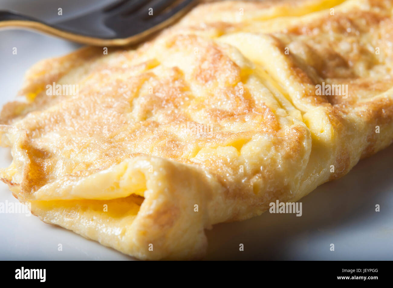 Close up (macro) of a cooked omelette, served on a white china plate ...