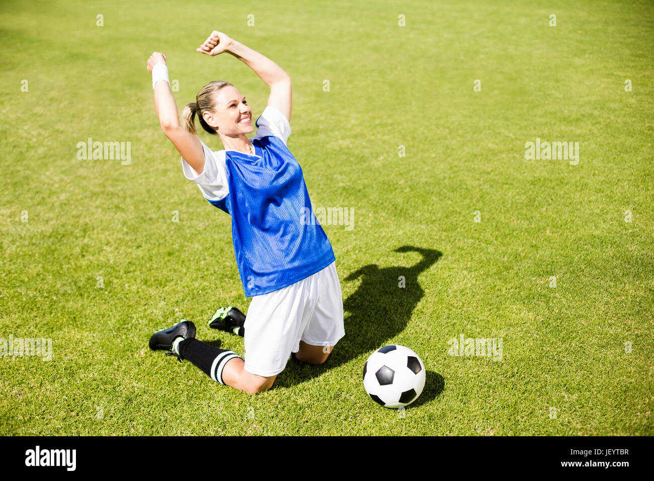 Excited football player kneeling in stadium Stock Photo - Alamy