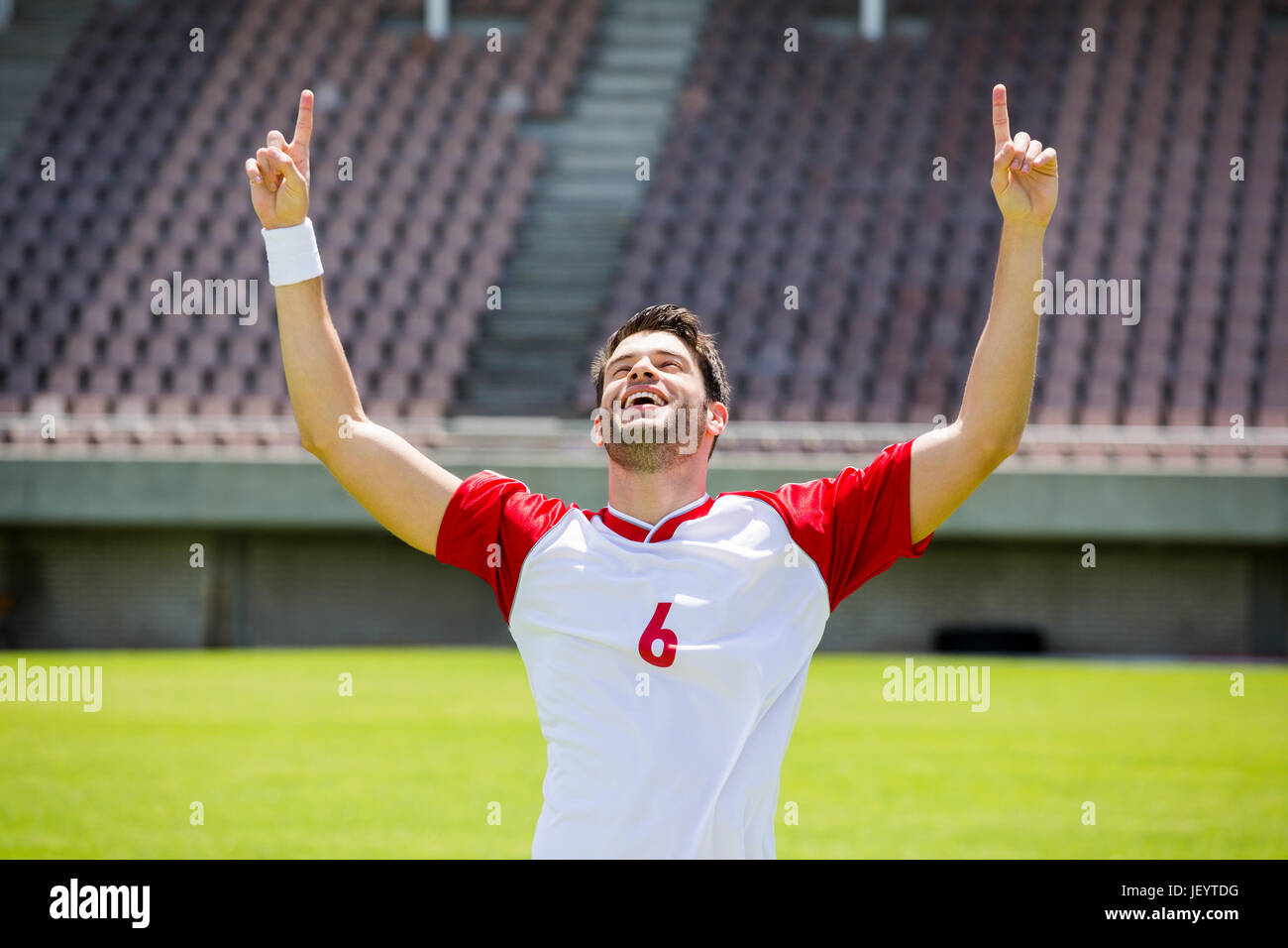 Excited football player with hands raised Stock Photo - Alamy