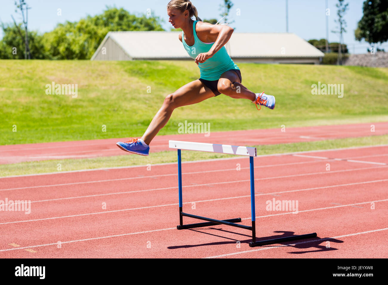 Female athlete jumping above the hurdle Stock Photo - Alamy