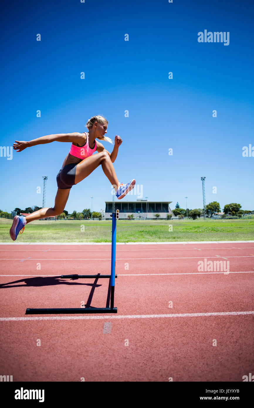 Female athlete jumping above the hurdle Stock Photo - Alamy