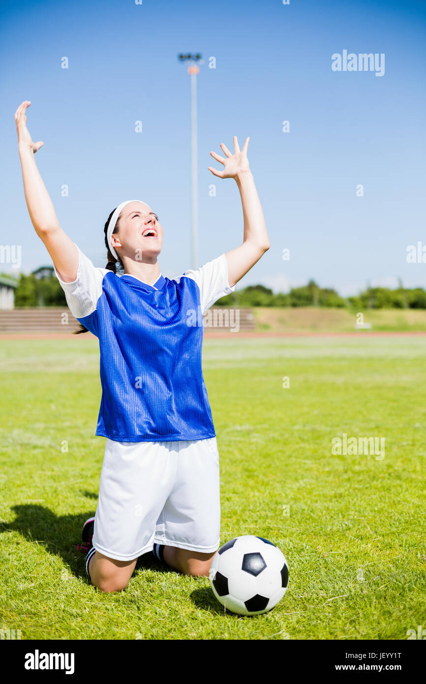 Excited young soccer player raised hand and kneeling down Stock Photo ...
