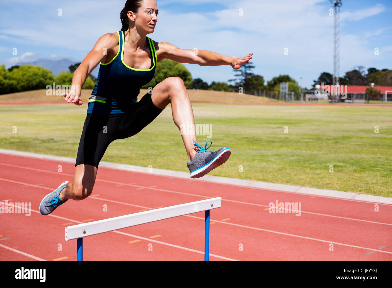 Female athlete jumping above the hurdle Stock Photo - Alamy