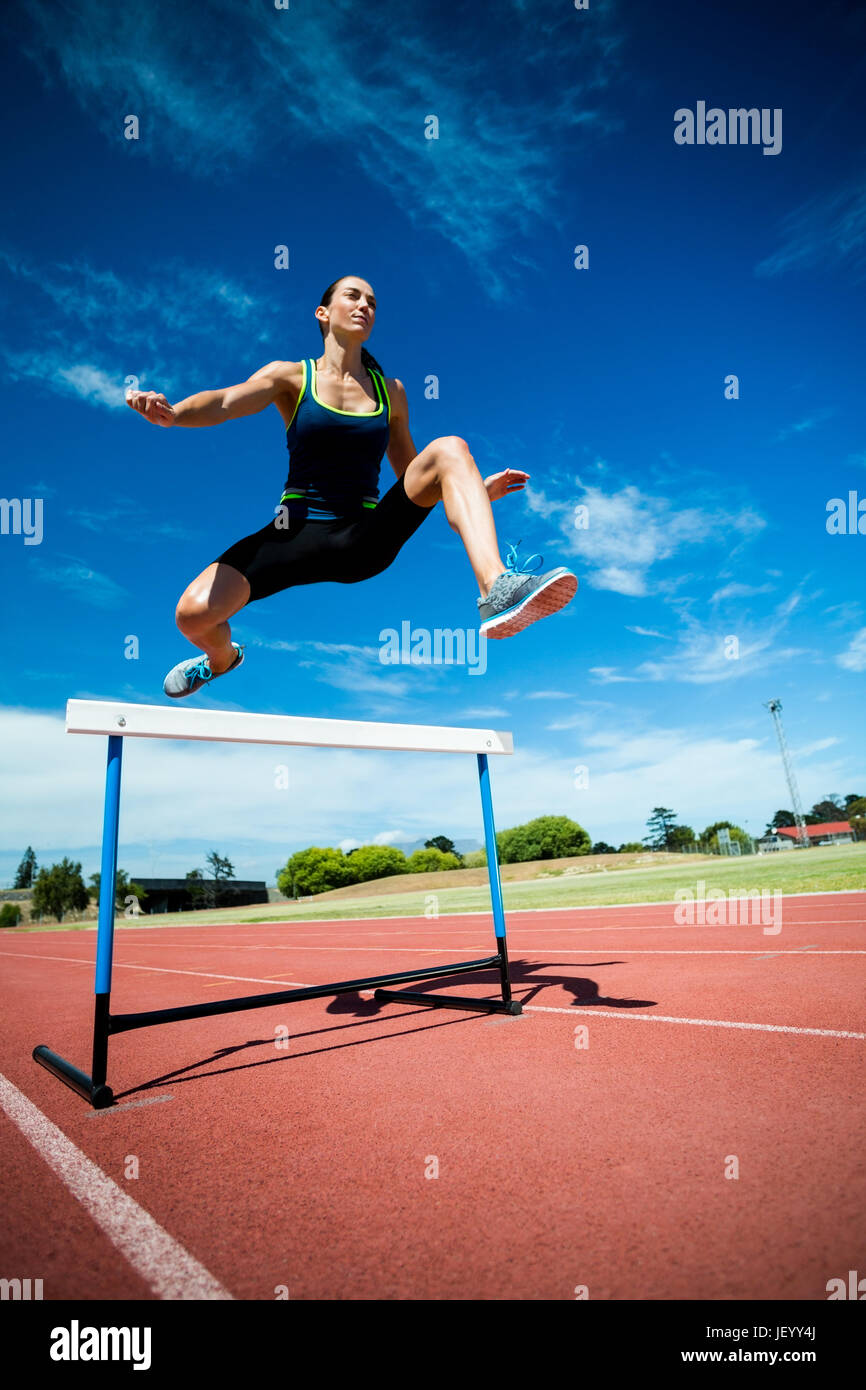 Female athlete jumping above the hurdle Stock Photo - Alamy
