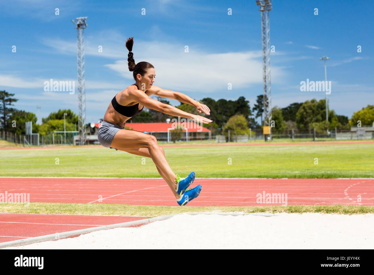 Female athlete performing a long jump Stock Photo - Alamy