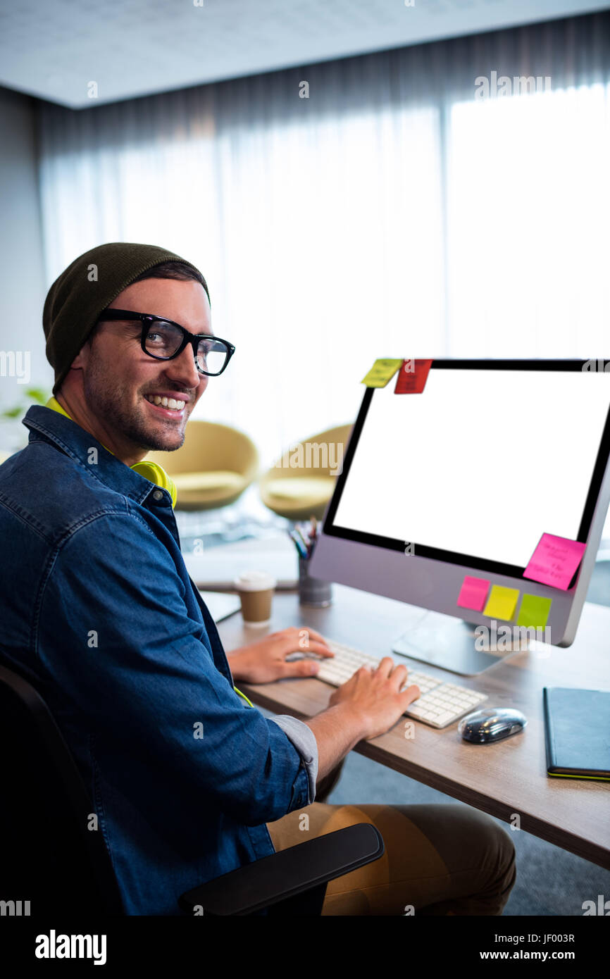 smiling casual man posing at computer desk Stock Photo - Alamy