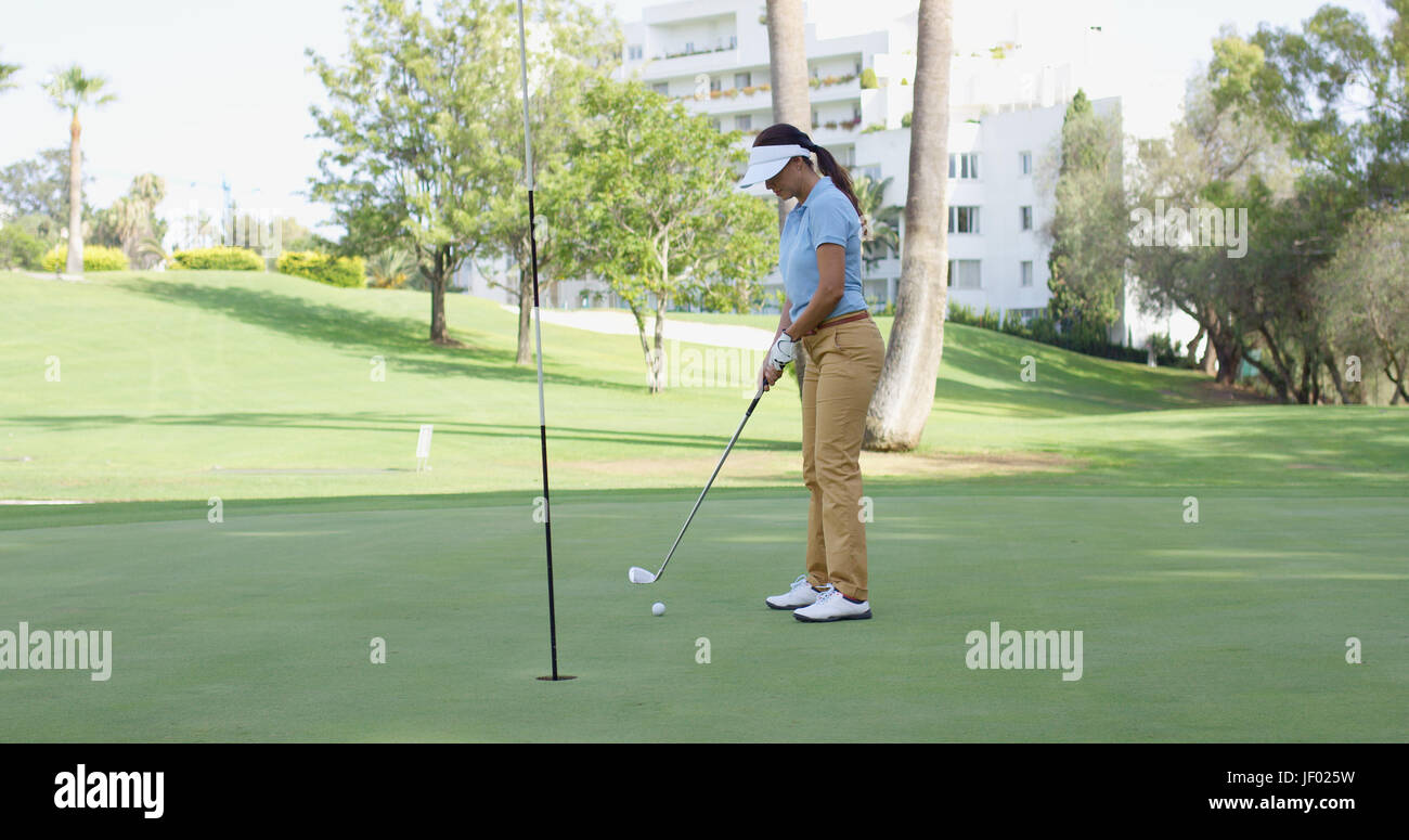 Woman golfer lining up for a putt Stock Photo - Alamy
