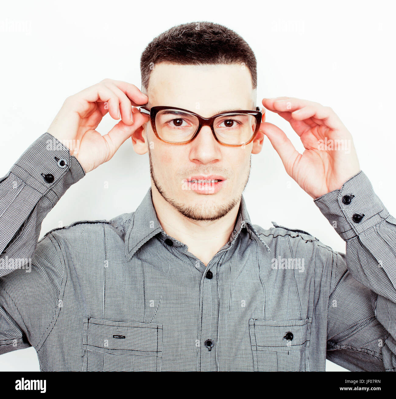 Portrait of a smart serious young man standing against white background ...