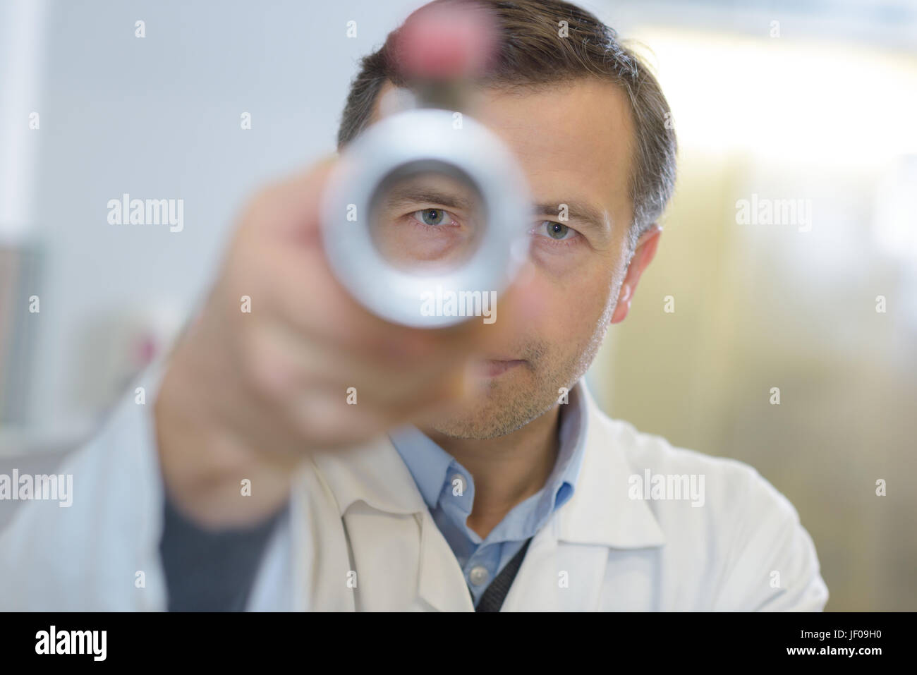 concentrated male doctor looking through a hole Stock Photo - Alamy