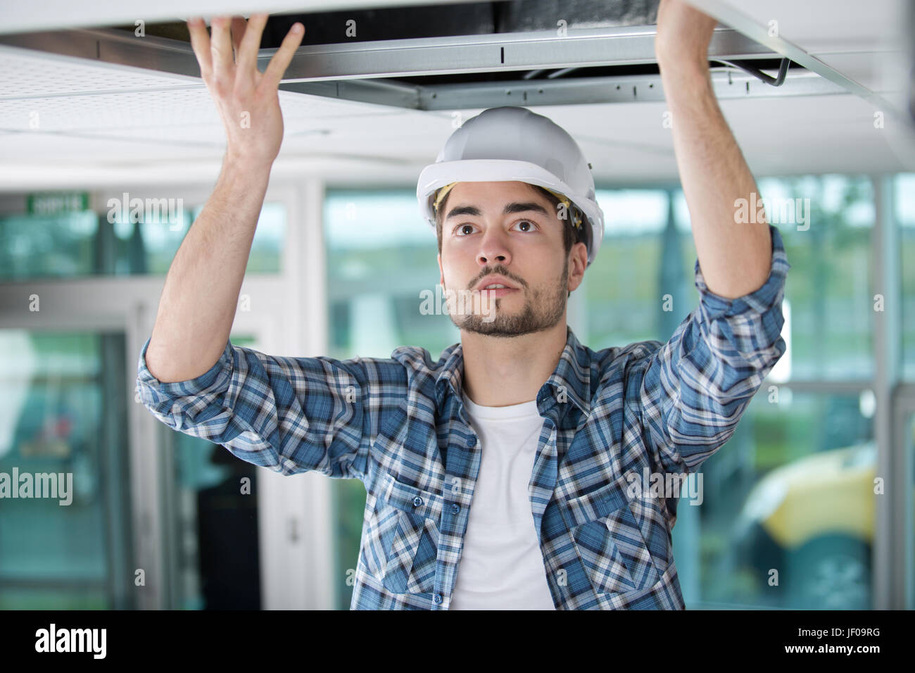 Contractor lifting ceiling panel Stock Photo - Alamy