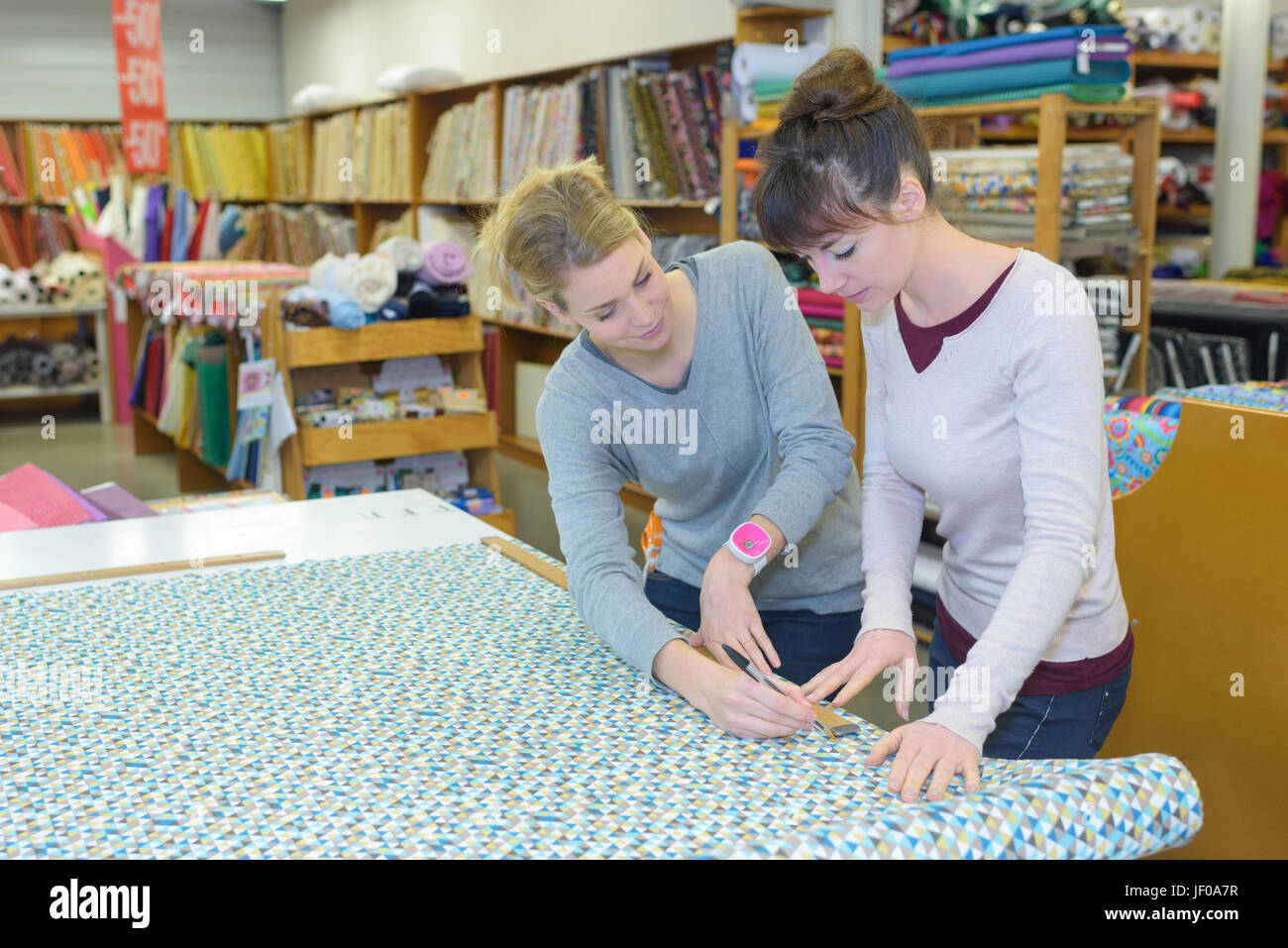 Women measuring material to buy Stock Photo - Alamy