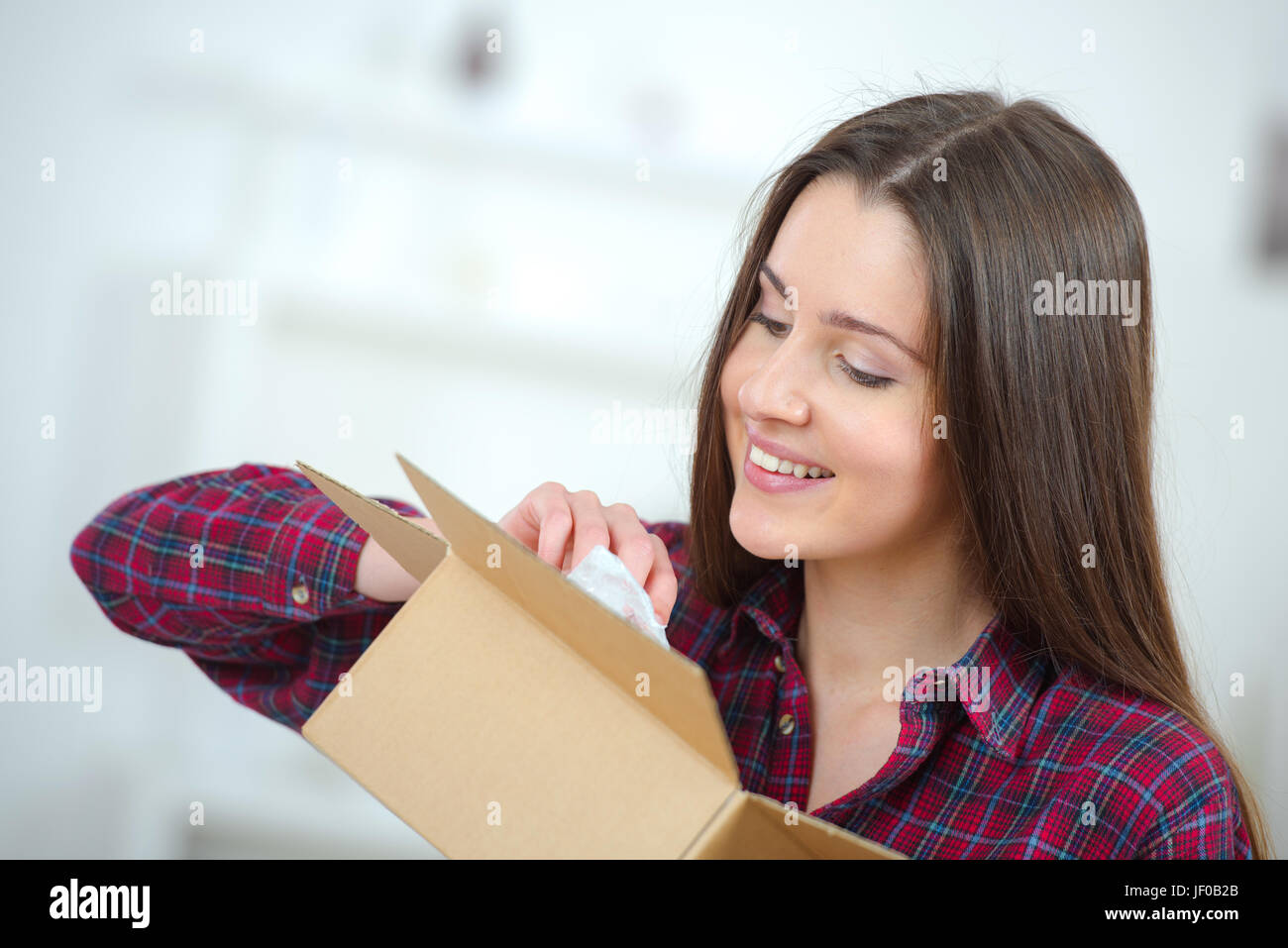 Girl taking contents from cardboard box Stock Photo - Alamy
