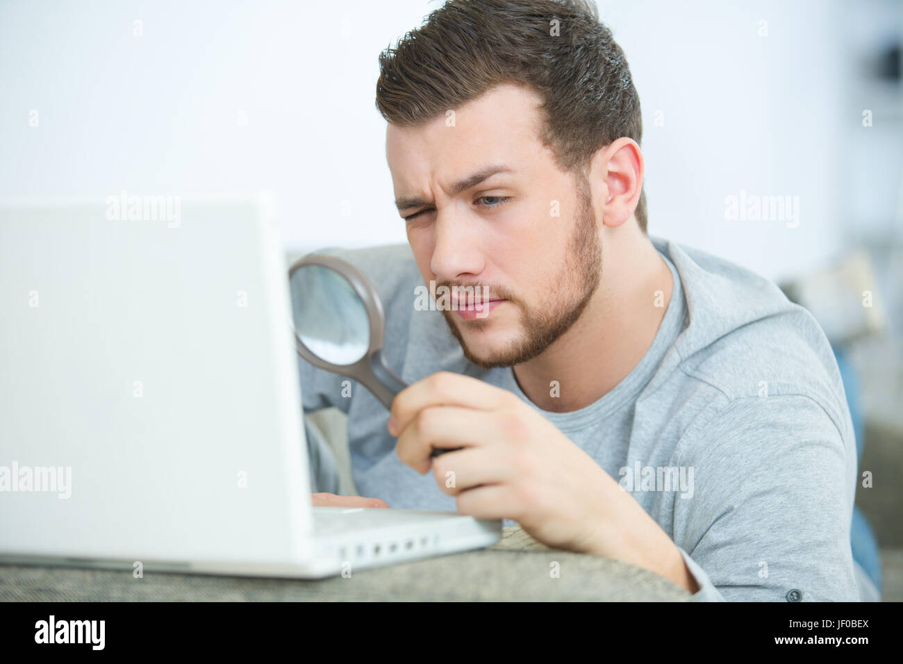 man looking at laptop through magnifying glass Stock Photo - Alamy