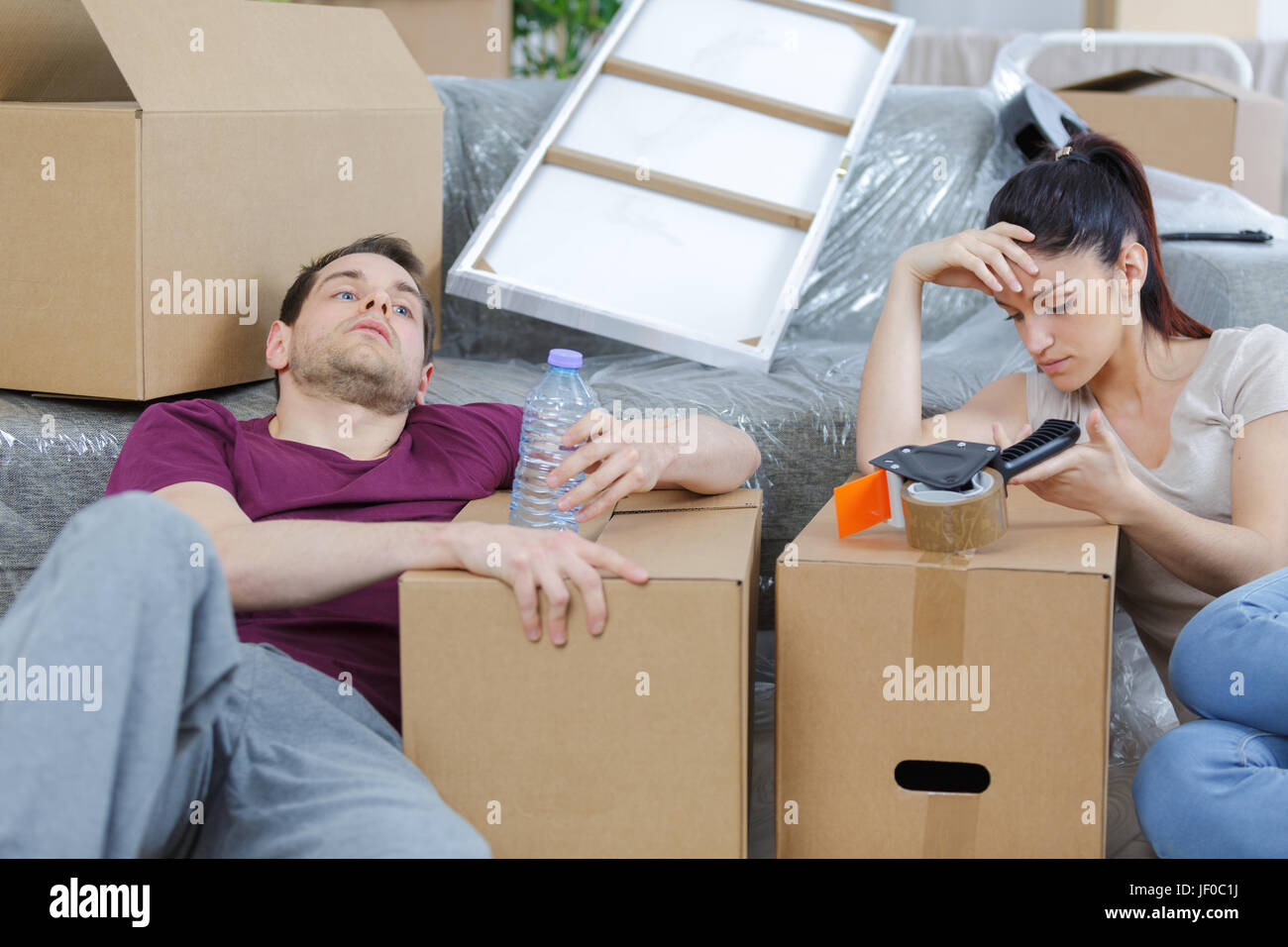 Exhausted young couple amongst boxes Stock Photo - Alamy