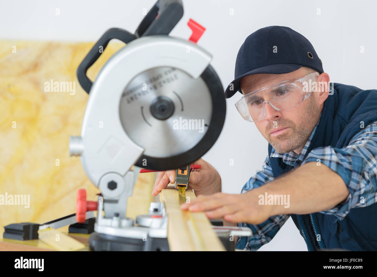 Workman using tape measure under circular saw Stock Photo - Alamy