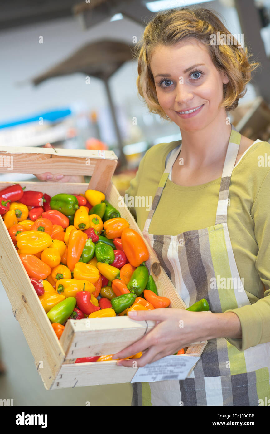 Shop assistant holding crate of peppers Stock Photo - Alamy