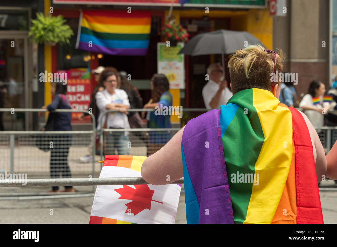 Toronto, CA - 25 June 2017: A girl with rainbow gay flag on her back at ...