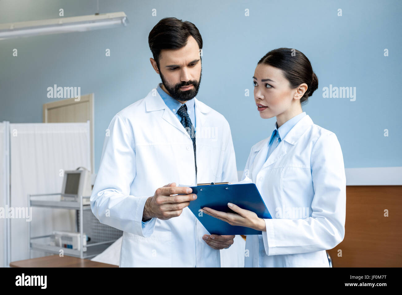 two doctors holding diagnosis and discussing in hospital chamber ...