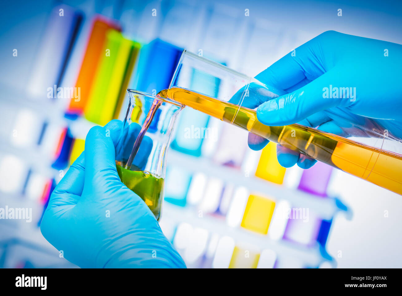 Scientist's hands holding a testing tube and a flask with colourful ...