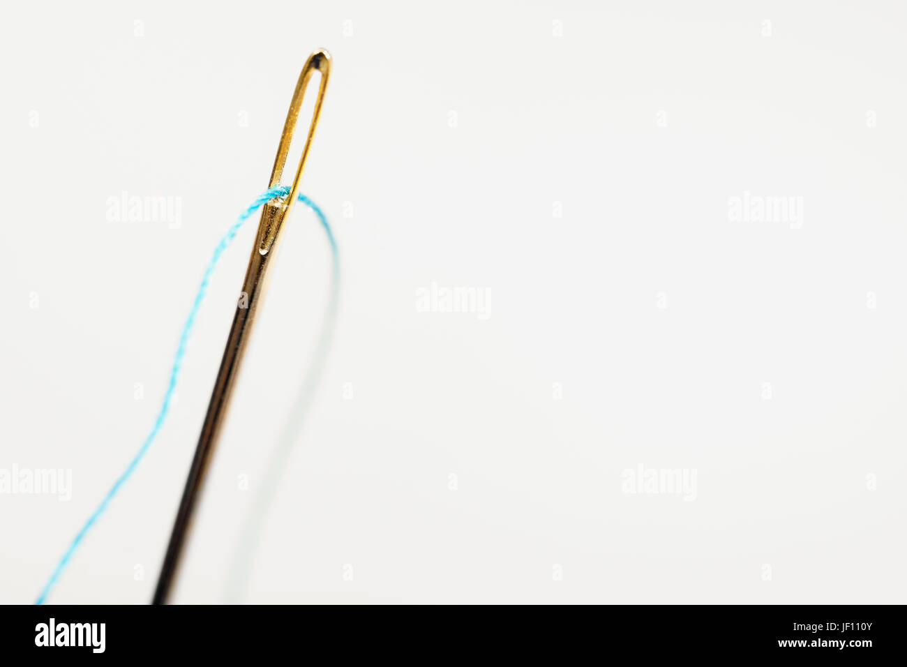 Sewing needle with blue thread through eye Stock Photo - Alamy