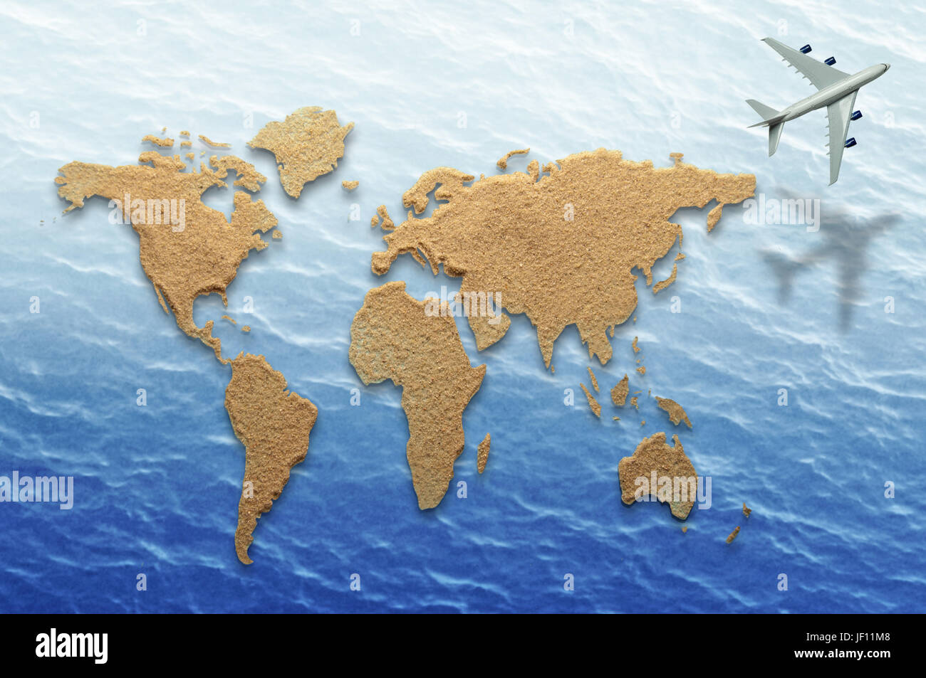 World atlas made from sand on sea background with airplane flying past ...