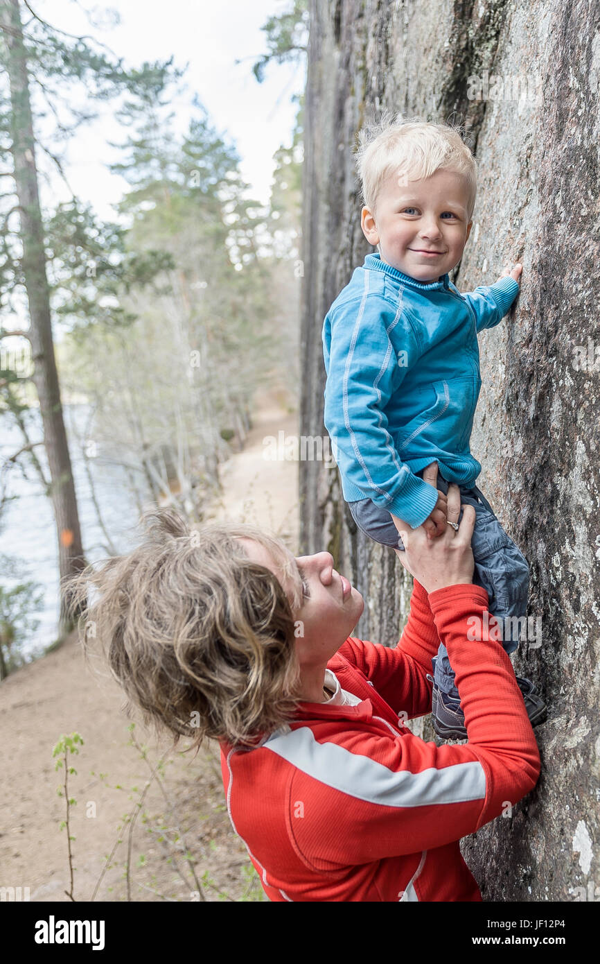 Mother helping boy to climb Stock Photo - Alamy