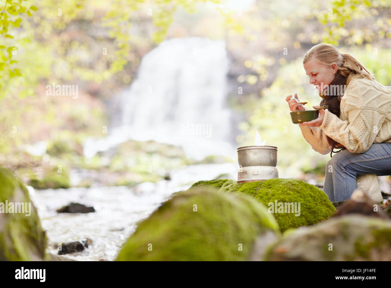 Woman eating near waterfall Stock Photo - Alamy