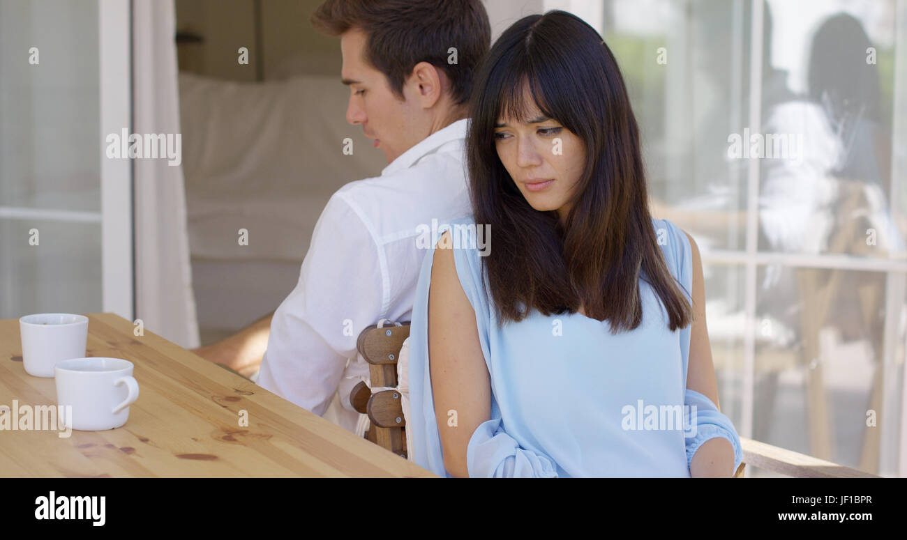 Angry couple sitting back to back at table Stock Photo - Alamy
