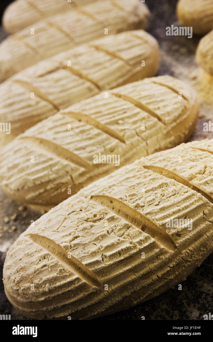 Close up high angle view of bread dough shaped into loaves, dusted with ...