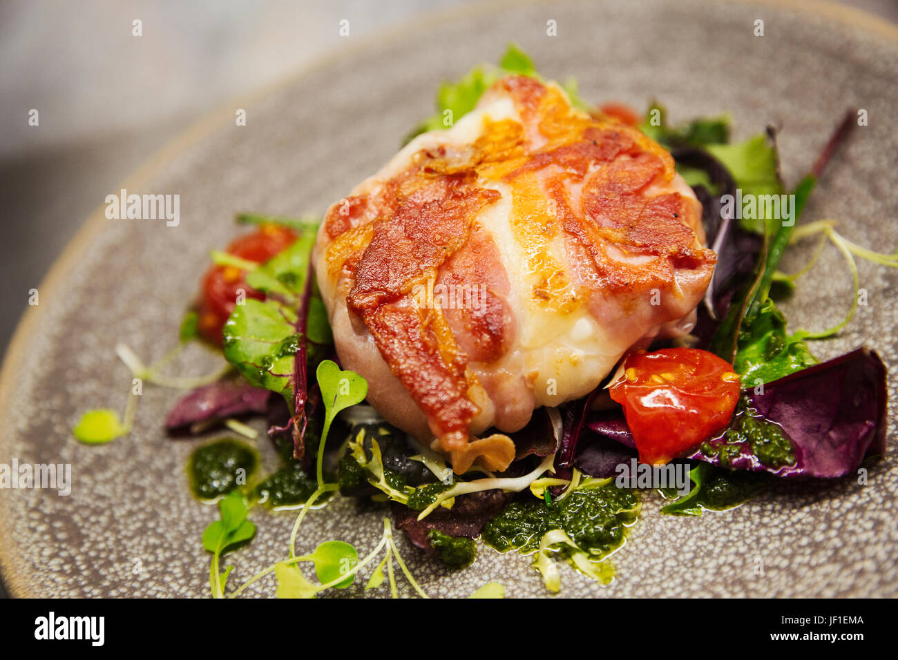 Close up high angle view of meat wrapped in bacon on a bed of salad on ...
