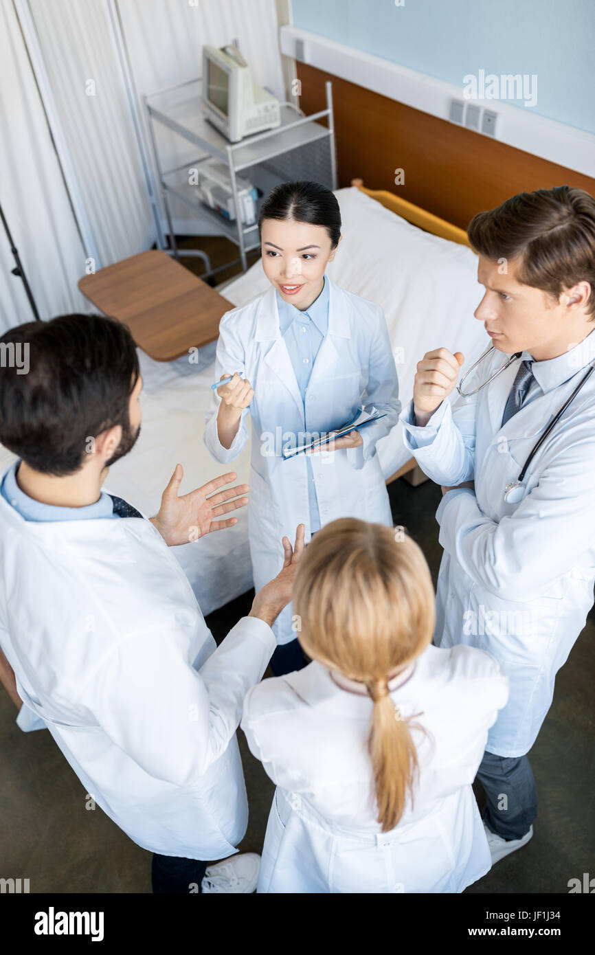 overhead view of doctors team discussing diagnosis in hospital, caring ...