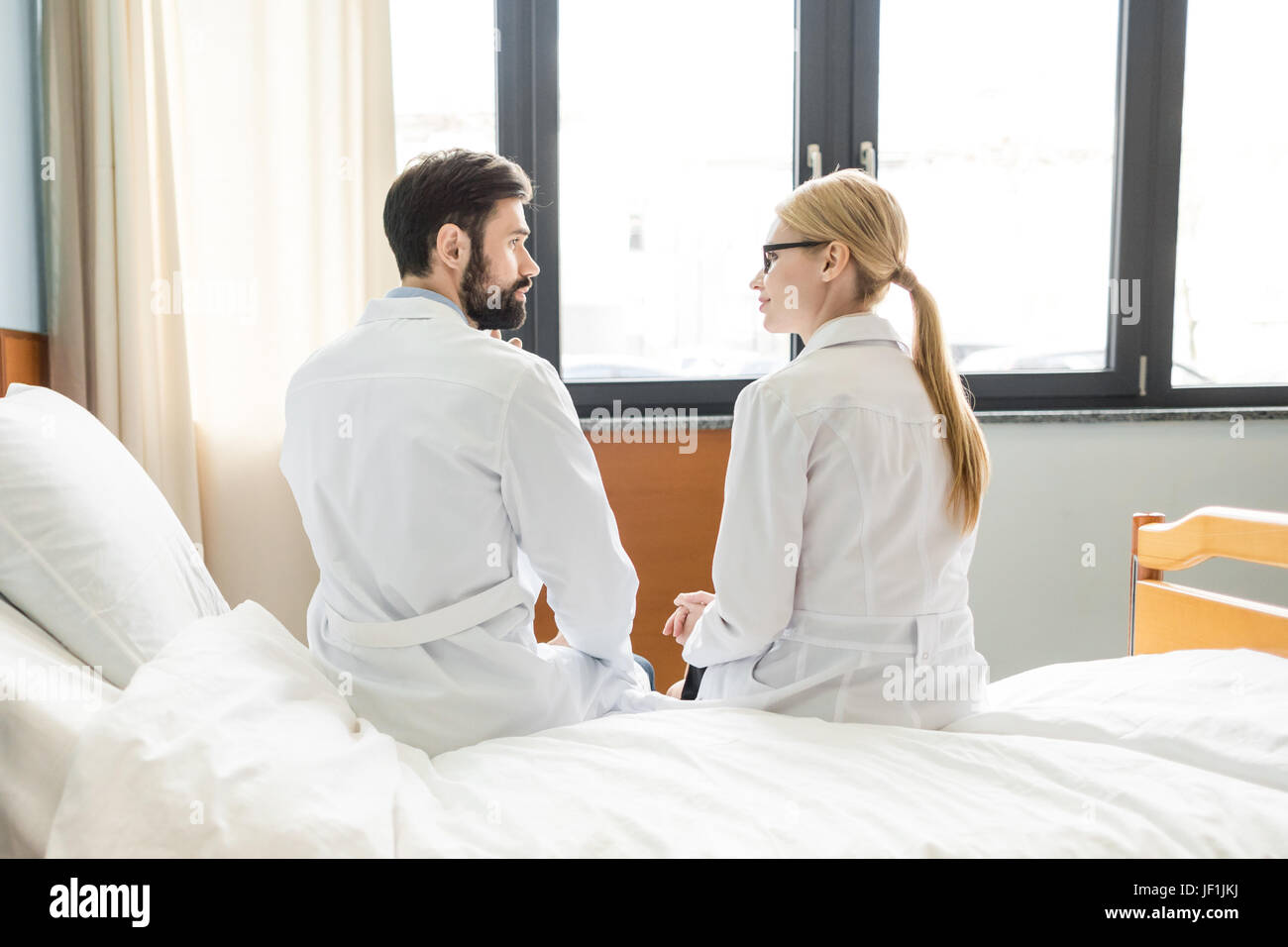 Back view of young professional doctors sitting on hospital bed and ...