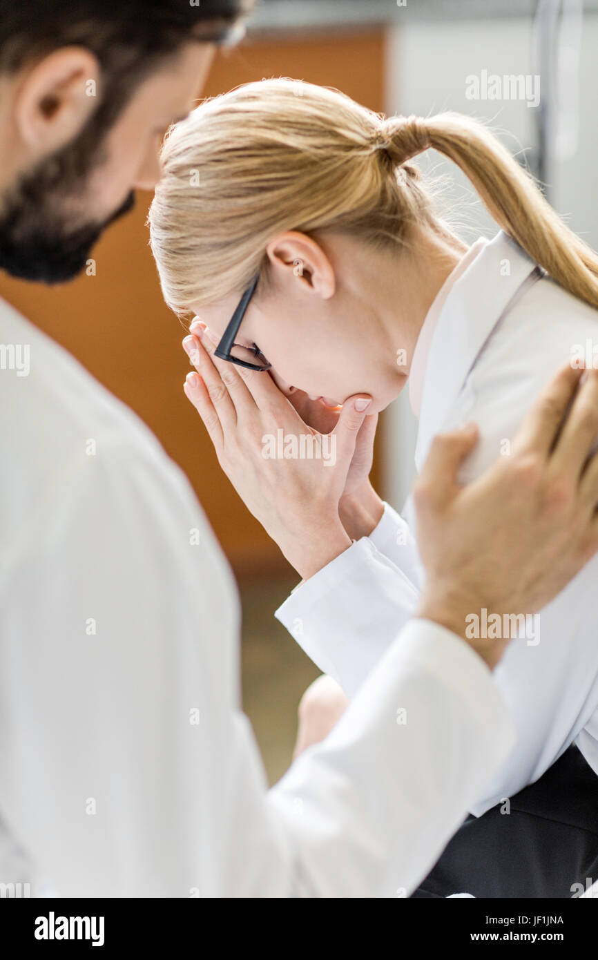 side view of doctor soothing upset colleague in hospital Stock Photo ...