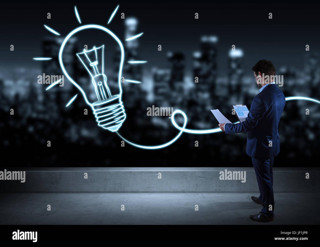 Businessman watching hand drawn lightbulb on a rooftop with a city view ...