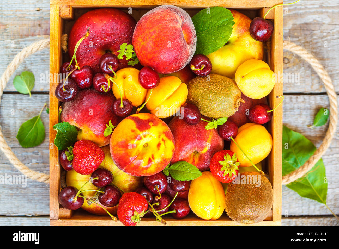 Summer fruits in a wooden box. Peaches, apricots, strawberries ...
