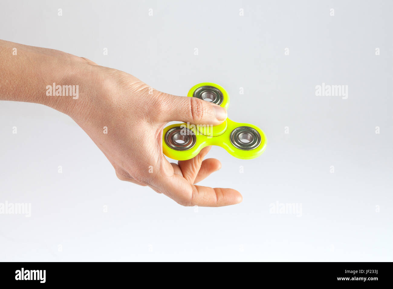 Female hand holding yellow fidget spinner isolated on white background ...