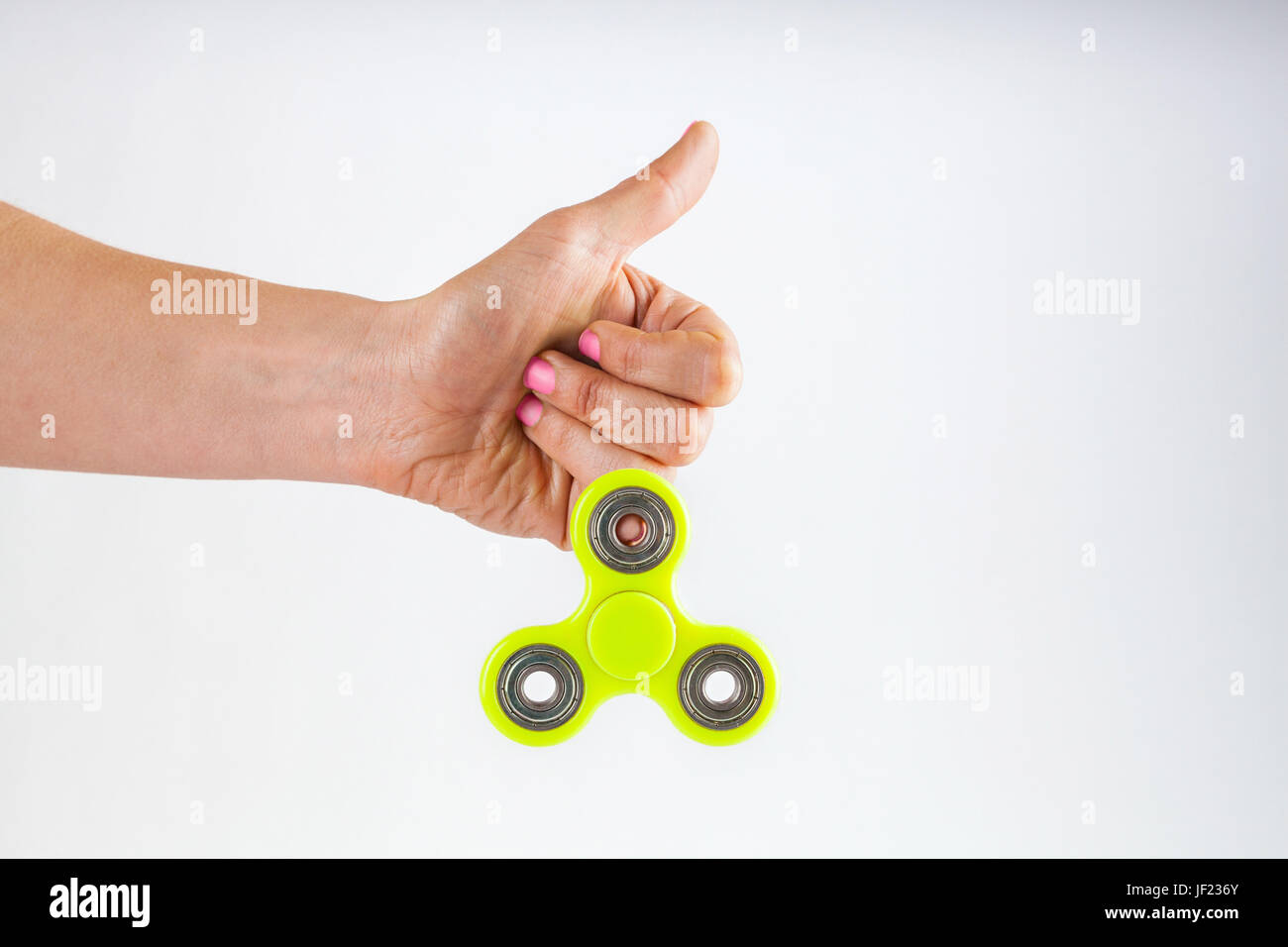 Female hand with pink nails holding yellow fidget spinner with thumb up ...