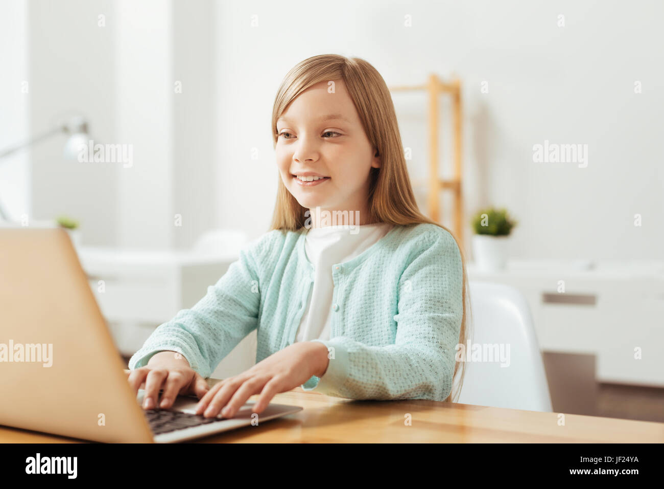 Bright energetic child typing something on her laptop Stock Photo - Alamy