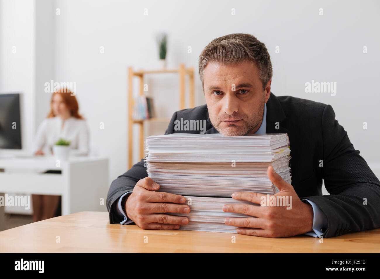 Persistent talented employee receiving a lot of papers working with ...