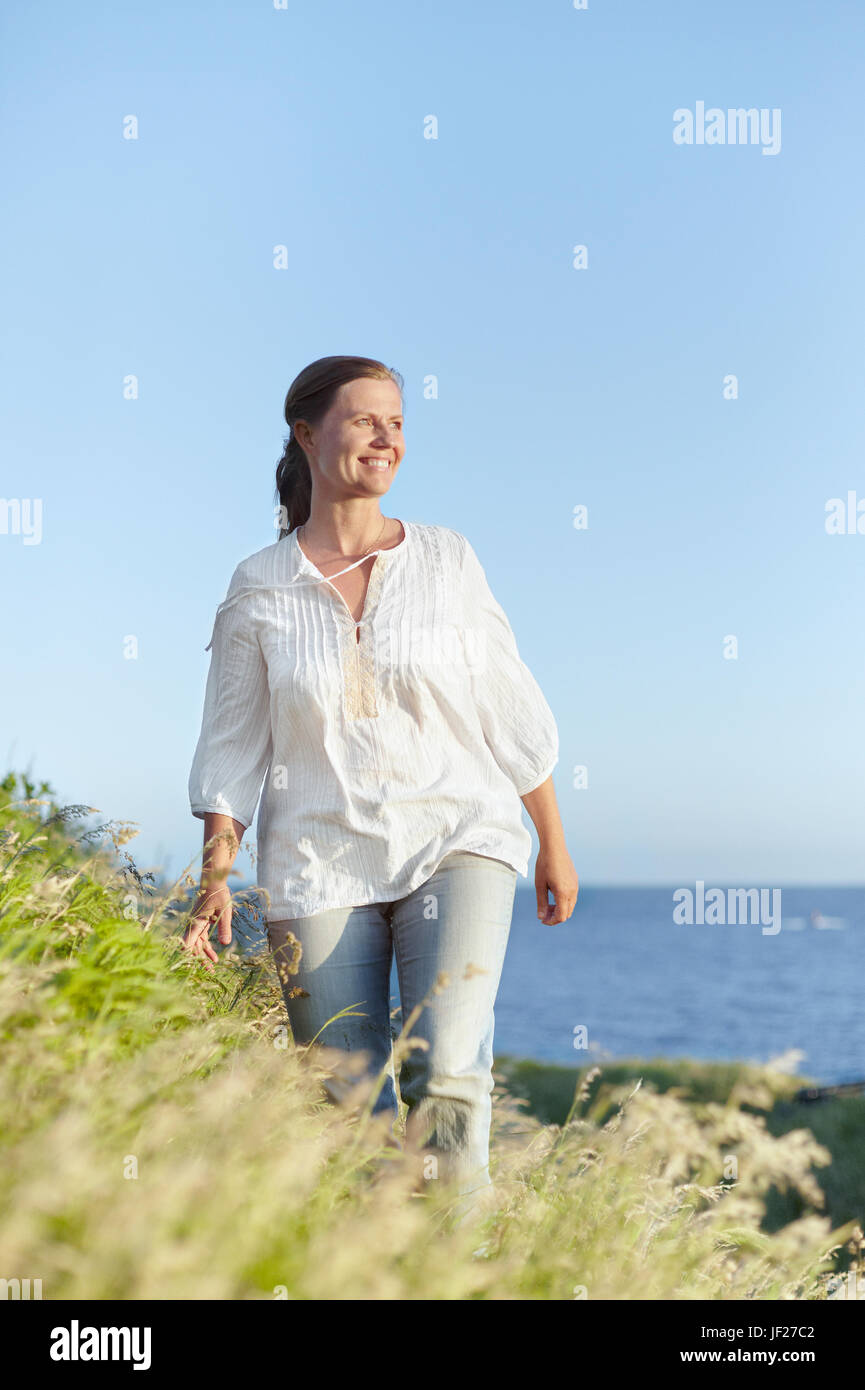 Smiling woman walking at sea Stock Photo - Alamy
