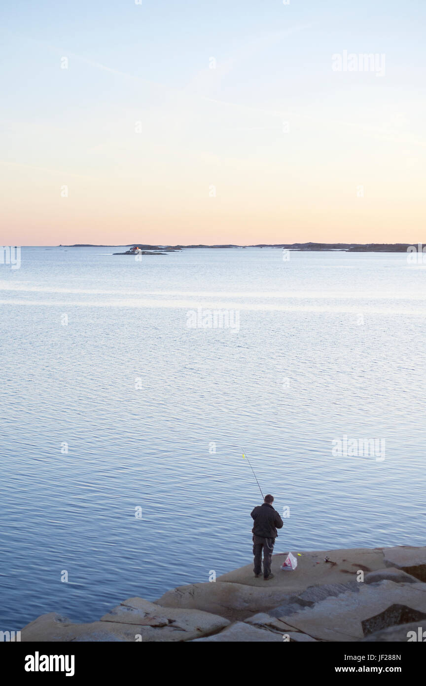 Man fishing at dusk Stock Photo - Alamy