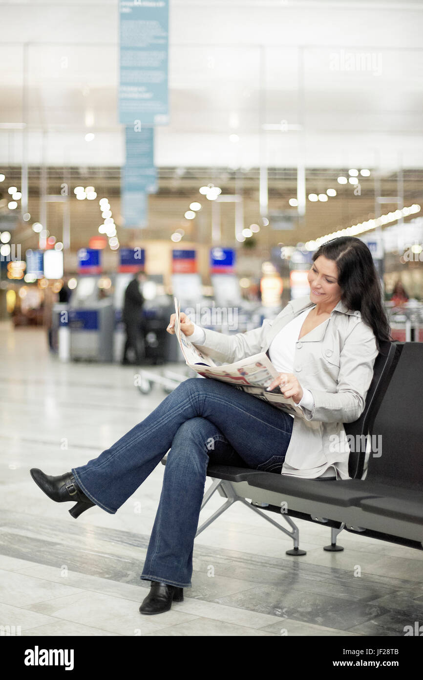 Young woman reading newspaper at airport Stock Photo - Alamy
