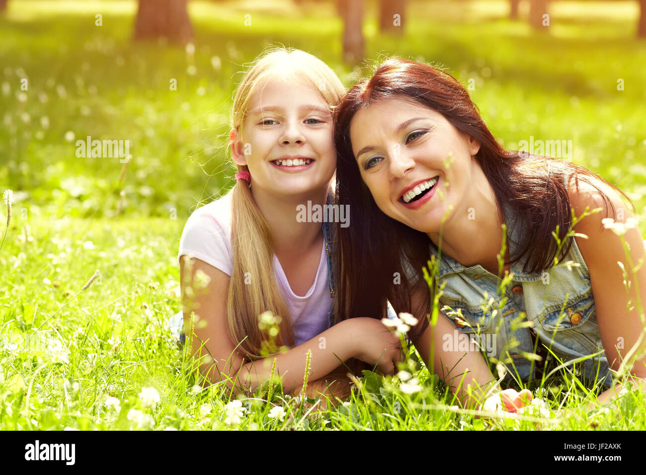 hugging happy mother and daughter for a walk in the park on light green background Stock Photo ...