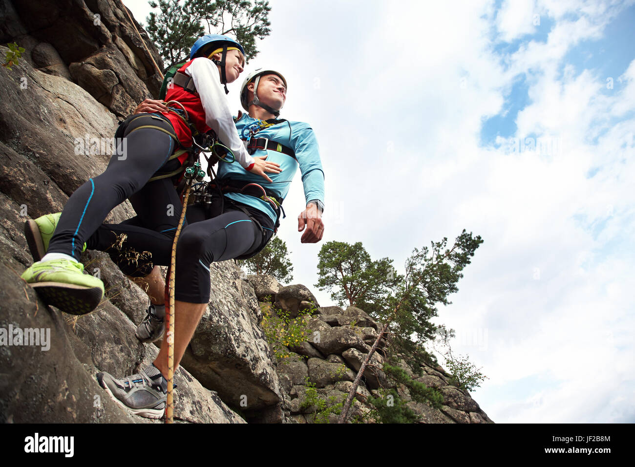 young couple in love climbers. man and woman hanging on a rock on the ...