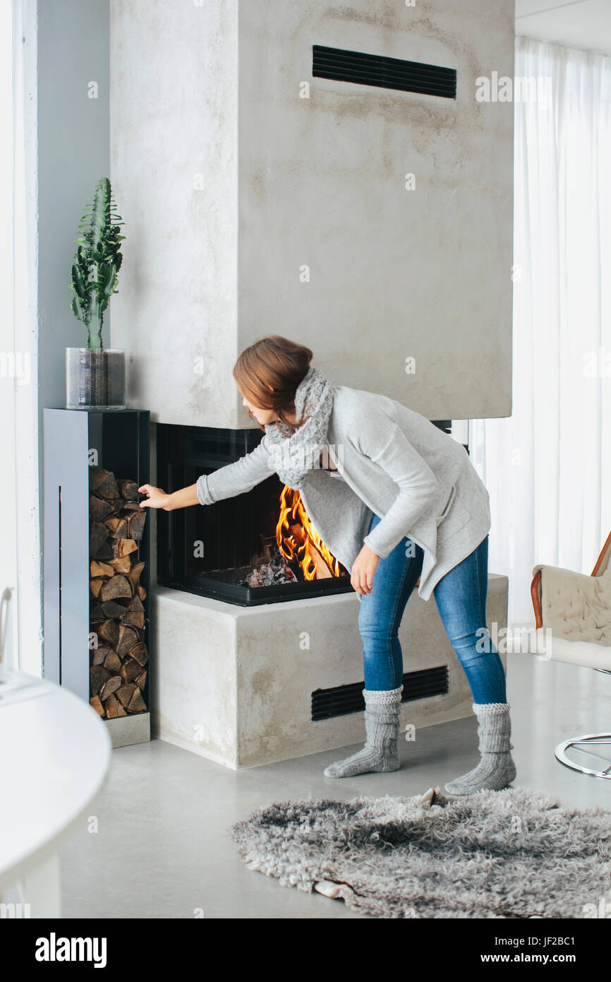 Woman putting firewood in fireplace Stock Photo - Alamy
