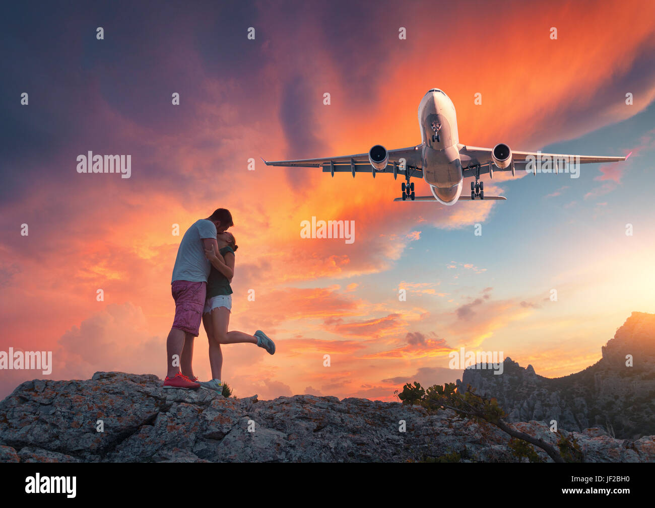 Airplane and hugging and kissing man and woman on the mountain peak at ...